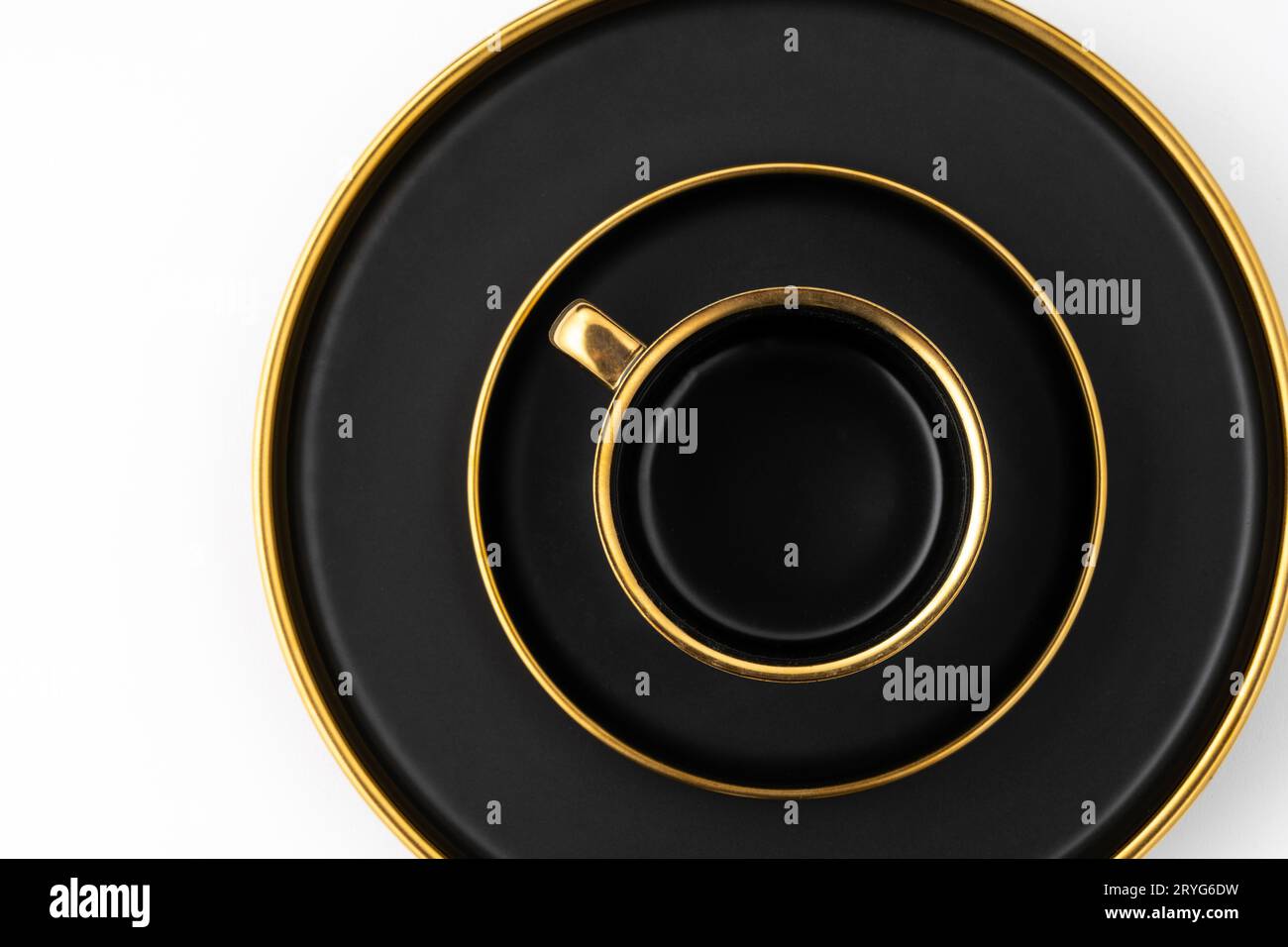 A set of black and golden ceramic plates and cup on a white background ...