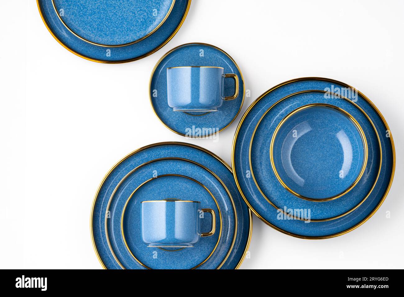 A set of blue ceramic plates and cup on a white background. Top view ...