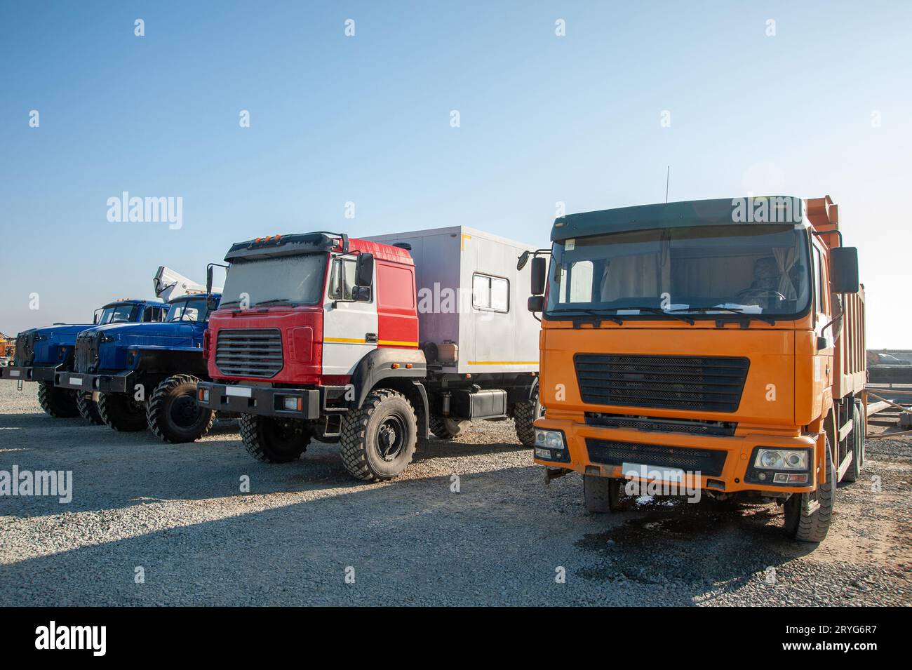 A row of large dump trucks and machines at a construction site Stock ...