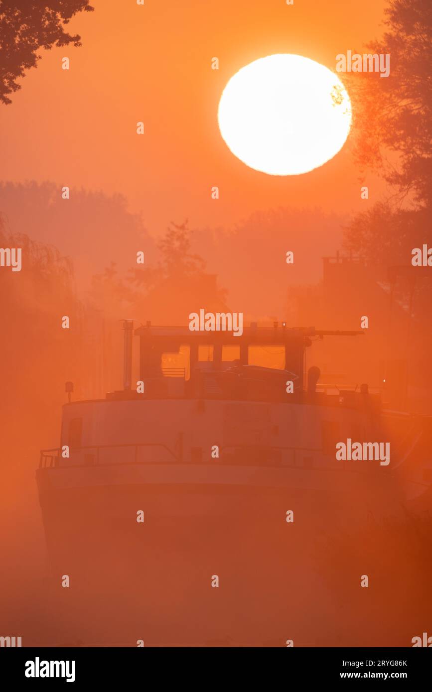 Silhouette of a cargo boat in the fiery red fog on a misty Morning on ...