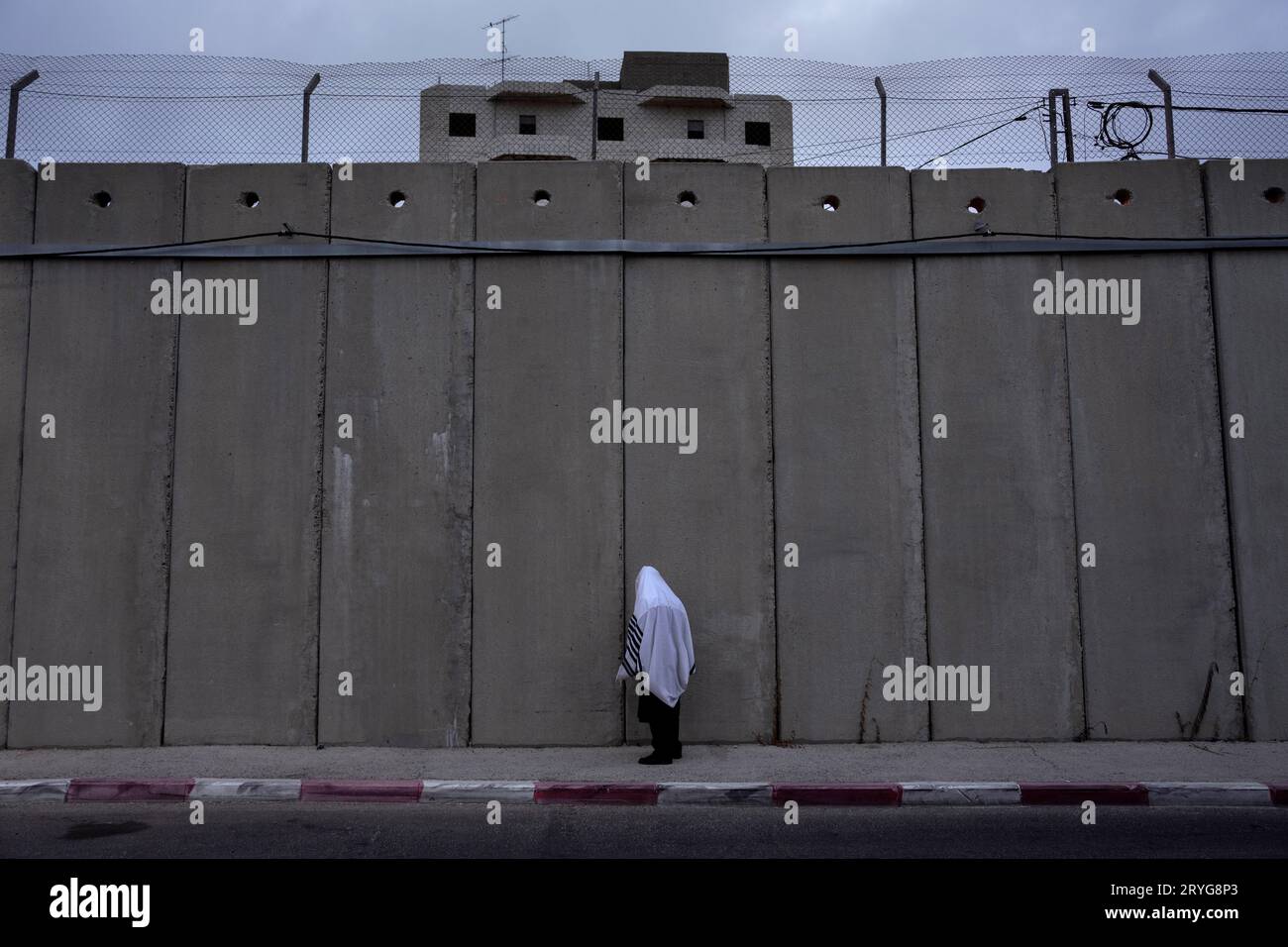 An ultra-Orthodox Jewish man prays next to the concrete separation ...