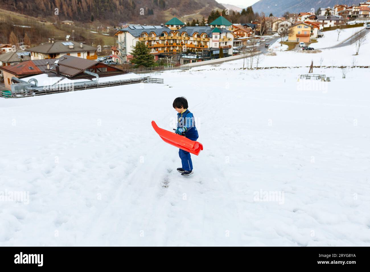 child girl with short dark hair in blue winter clothes going up the ...
