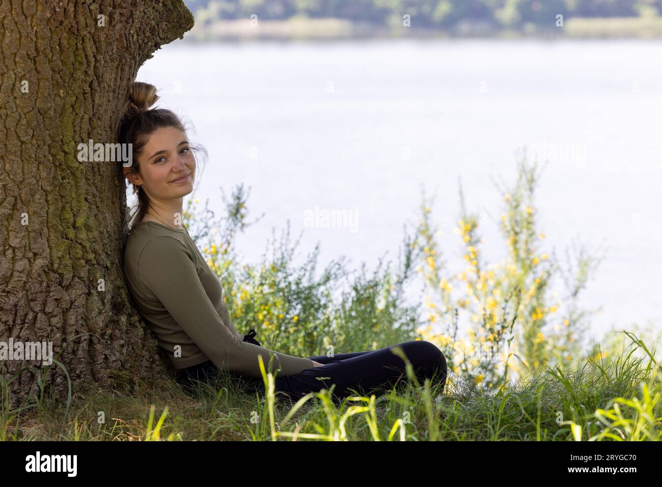 Young brunette woman sitting in green forest enjoys the silence and ...
