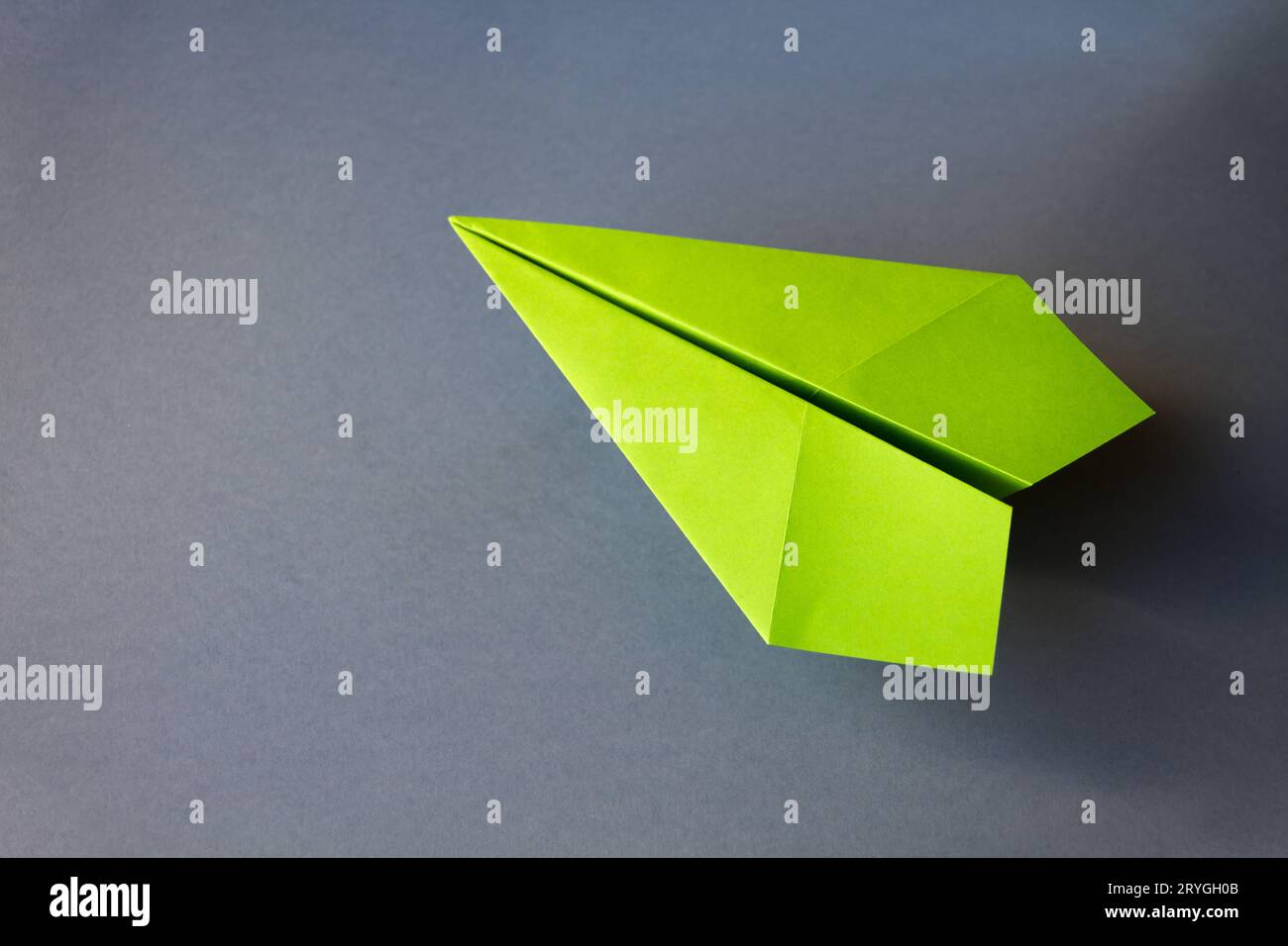 Green paper plane origami isolated on a grey background Stock Photo - Alamy