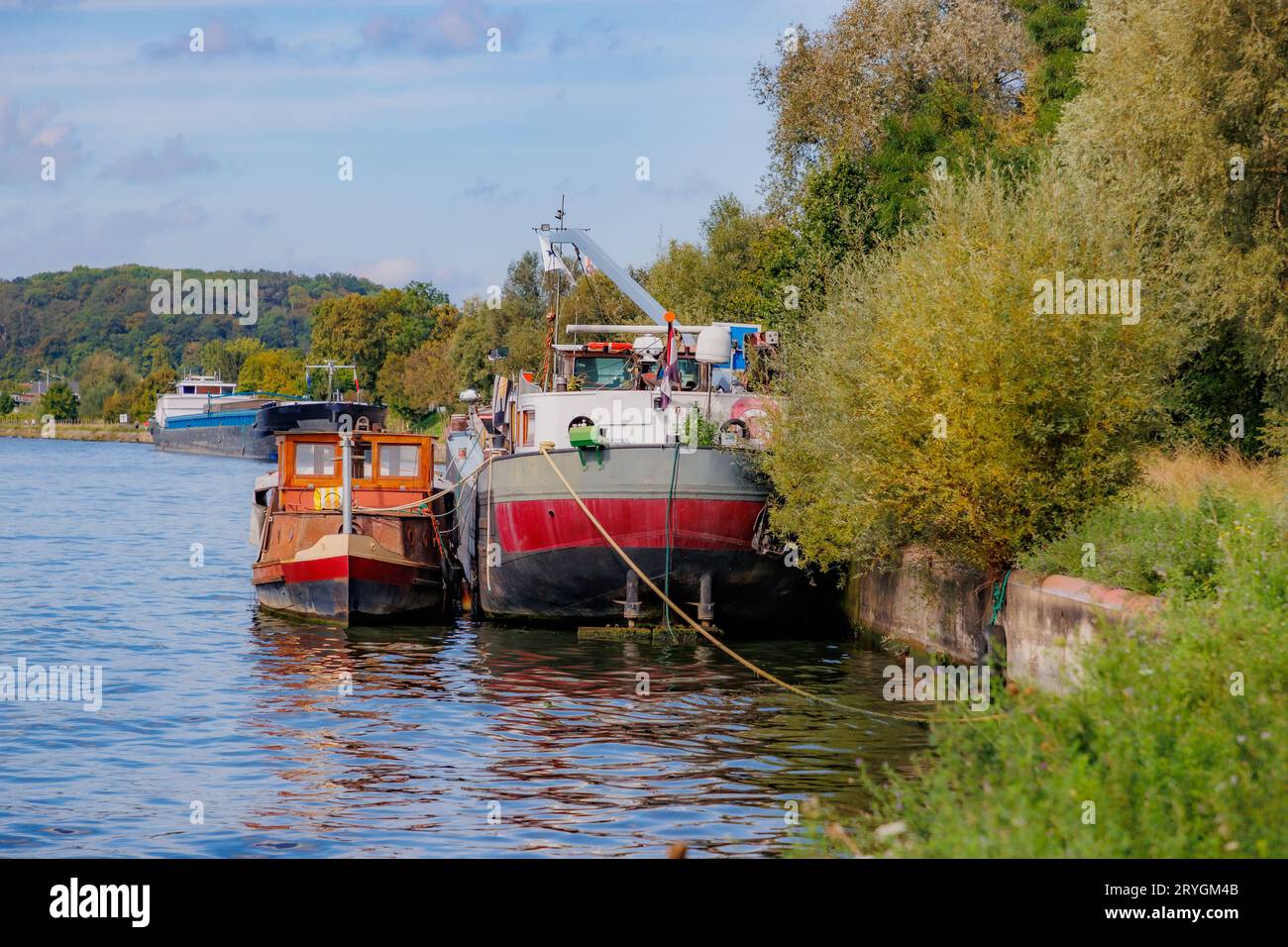 Two boats anchored at a dock berth on Albert Canal, cargo ship in ...