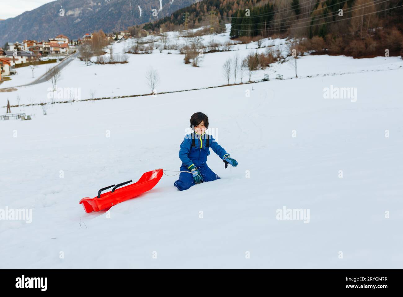 child girl with short dark hair in blue winter clothes going up the ...