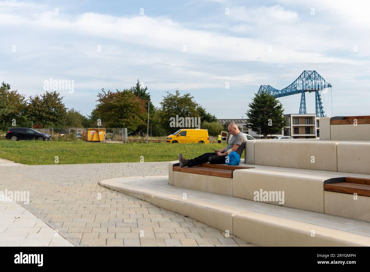 A man sits in a public seating area by the Boho redevelopment area of ...