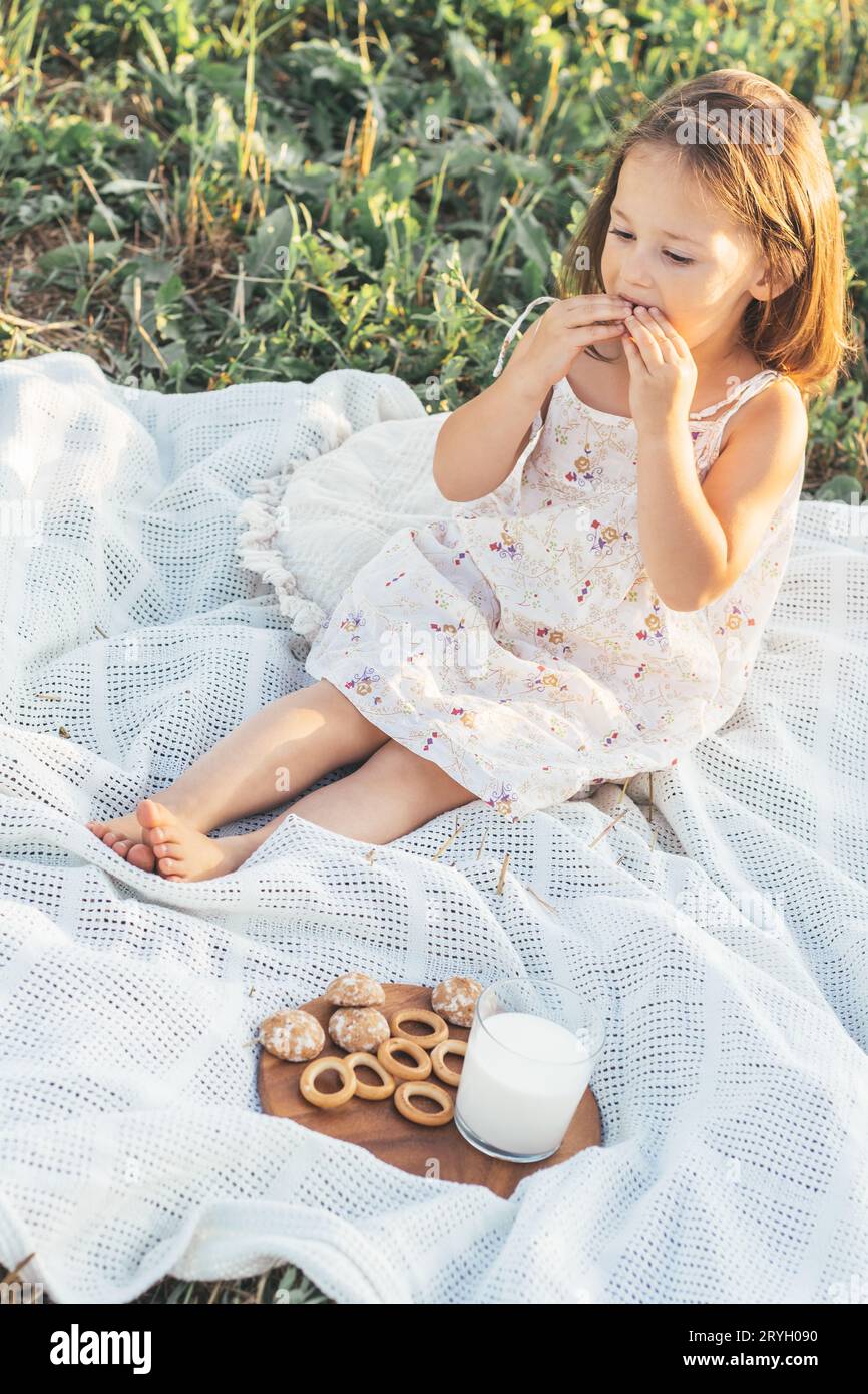 Little beautiful girl in summer colorful sundress has breakfast with ...