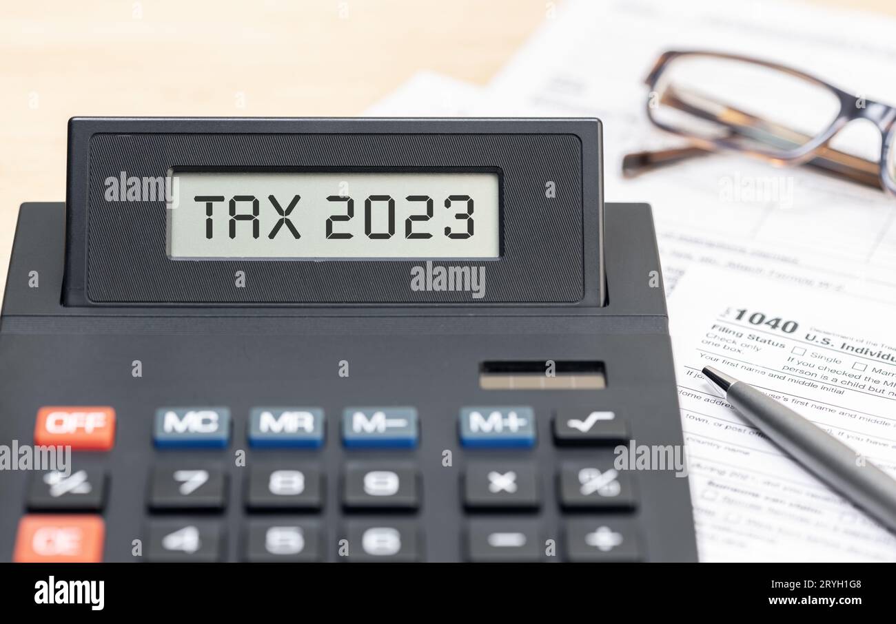 Tax time 2023 concept. Text on calculator screen and tax form on table ...