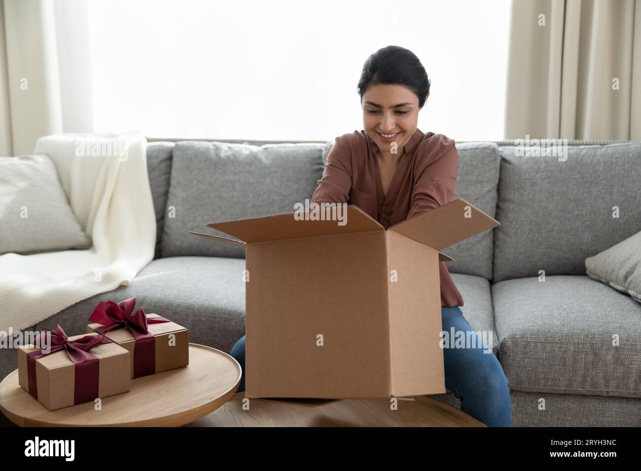 Excited Indian woman unpacking parcel with wrapped gift boxes Stock Photo - Alamy
