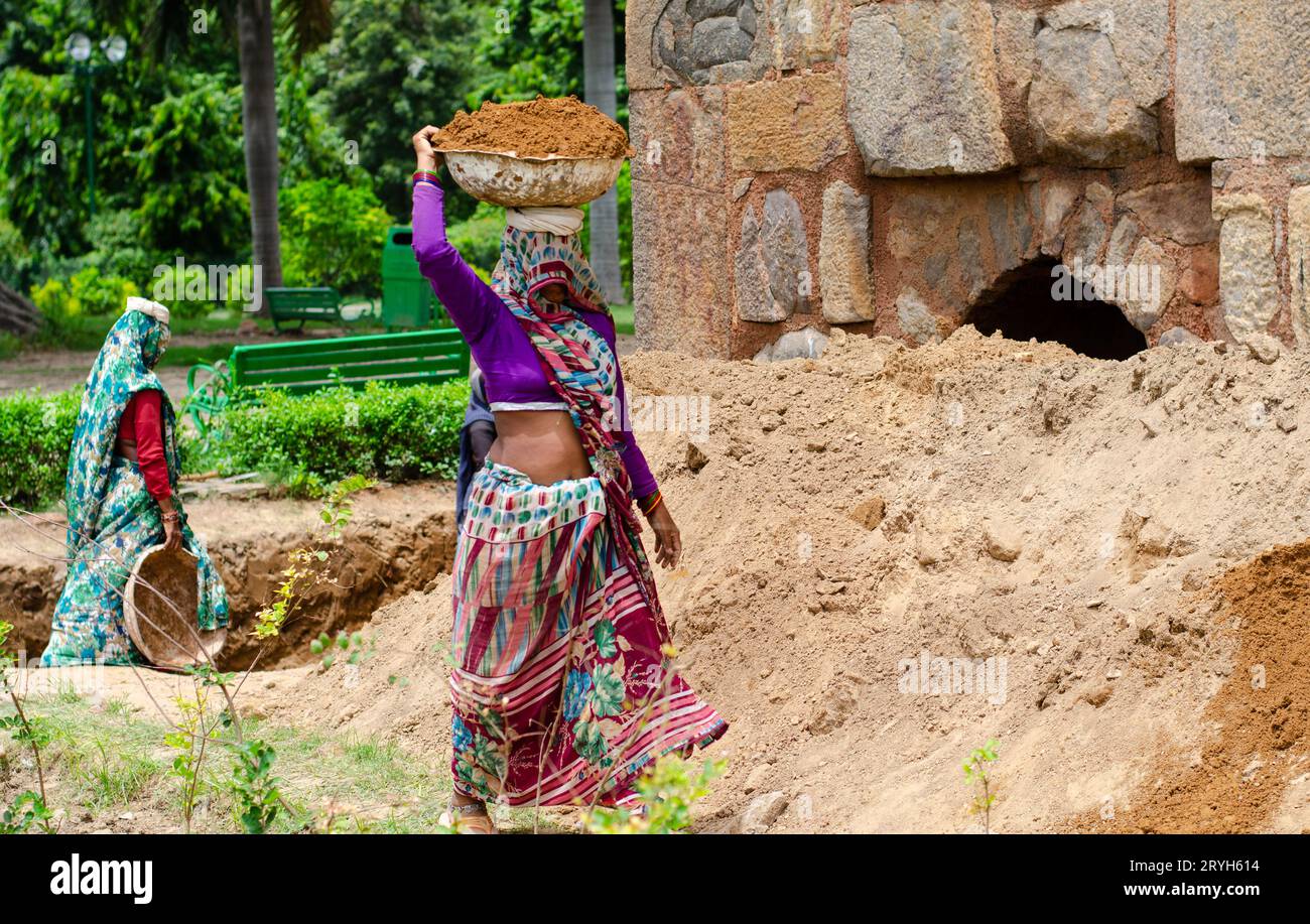 Indian women working on construction industry outdoors carrying sand on ...