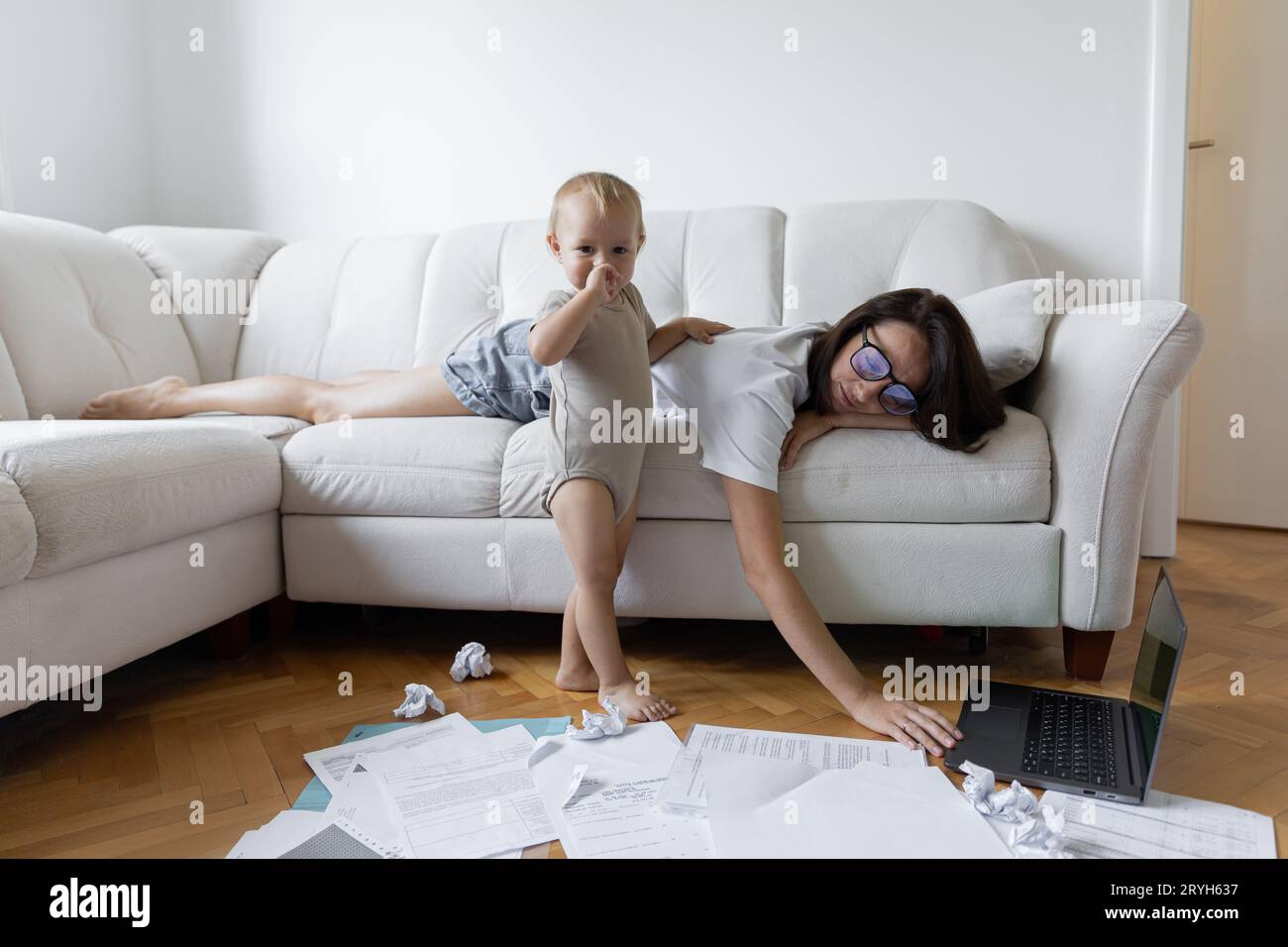 Young girl sitting on the couch and trying to work next to the child ...