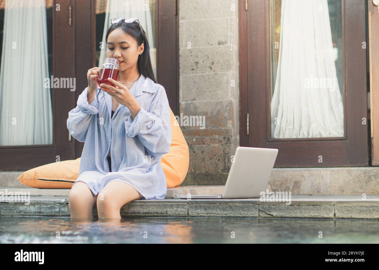 Woman using laptop for working around swimming pool Stock Photo - Alamy