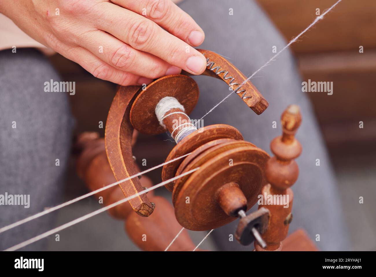 The closeup shot shows a hand spinning thread on a vintage spinning ...