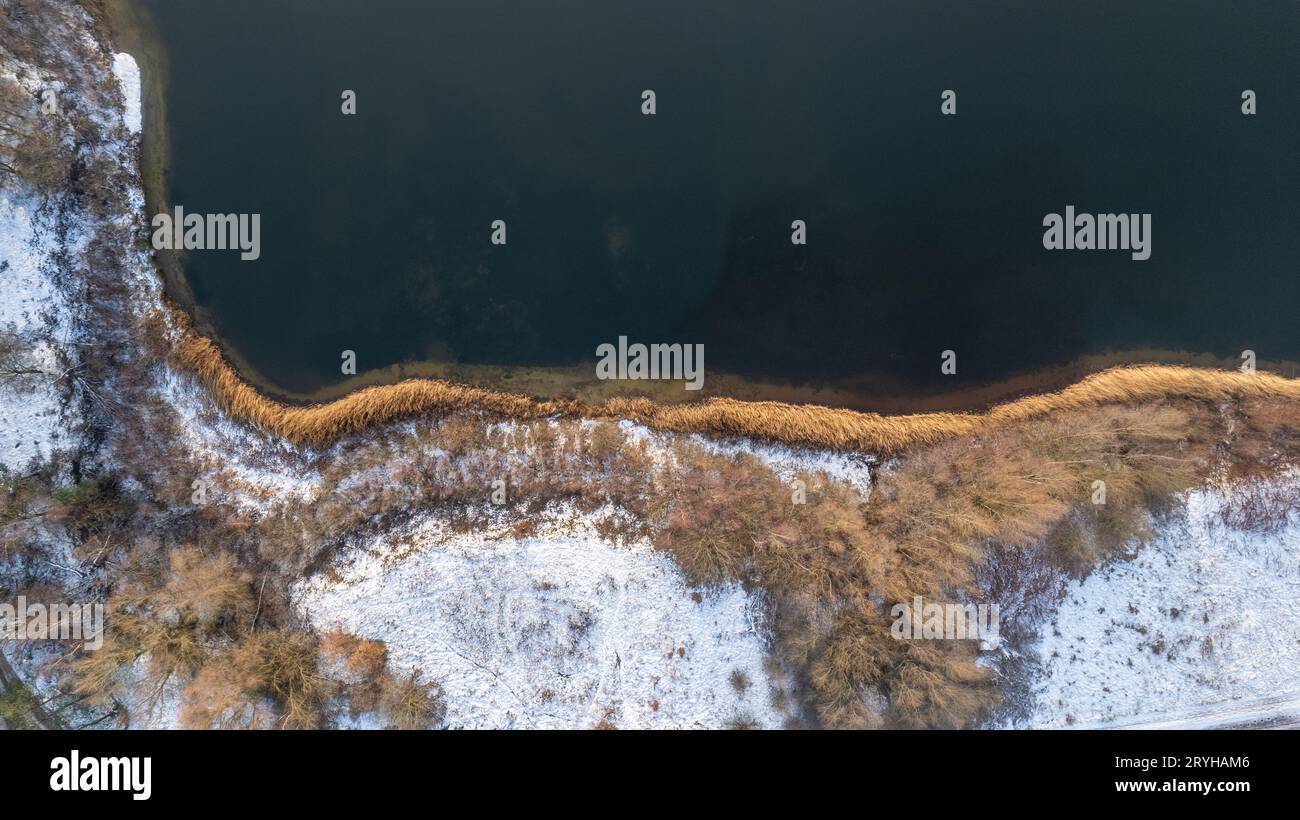 Aerial view of the winter snow covered forest and frozen lake from ...