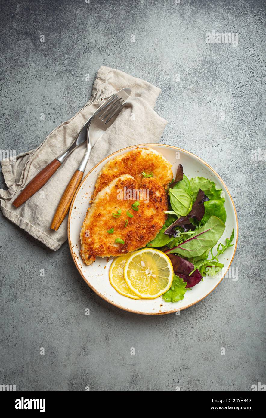 Crispy panko breaded fried chicken fillet with green salad and lemon on ...