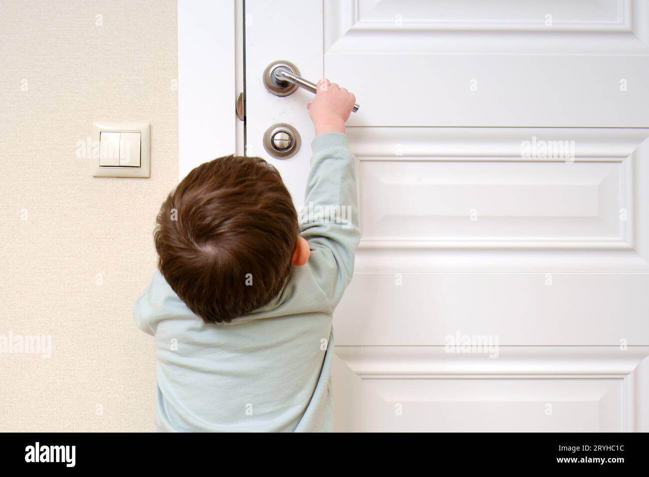 Little baby opens the door. Child pulls the door handle with the lock ...