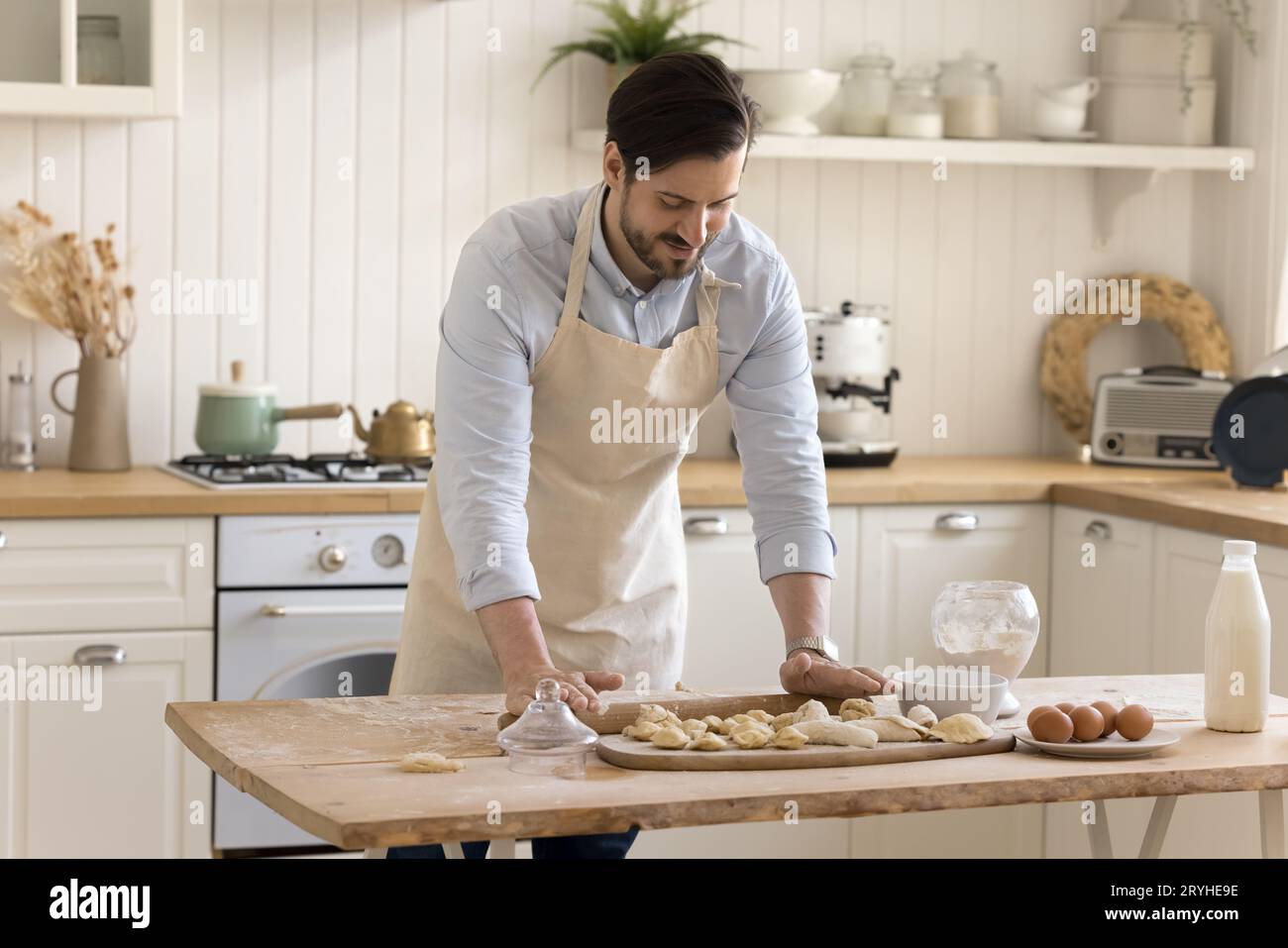 Positive young man flattening dough with rolling pin Stock Photo - Alamy