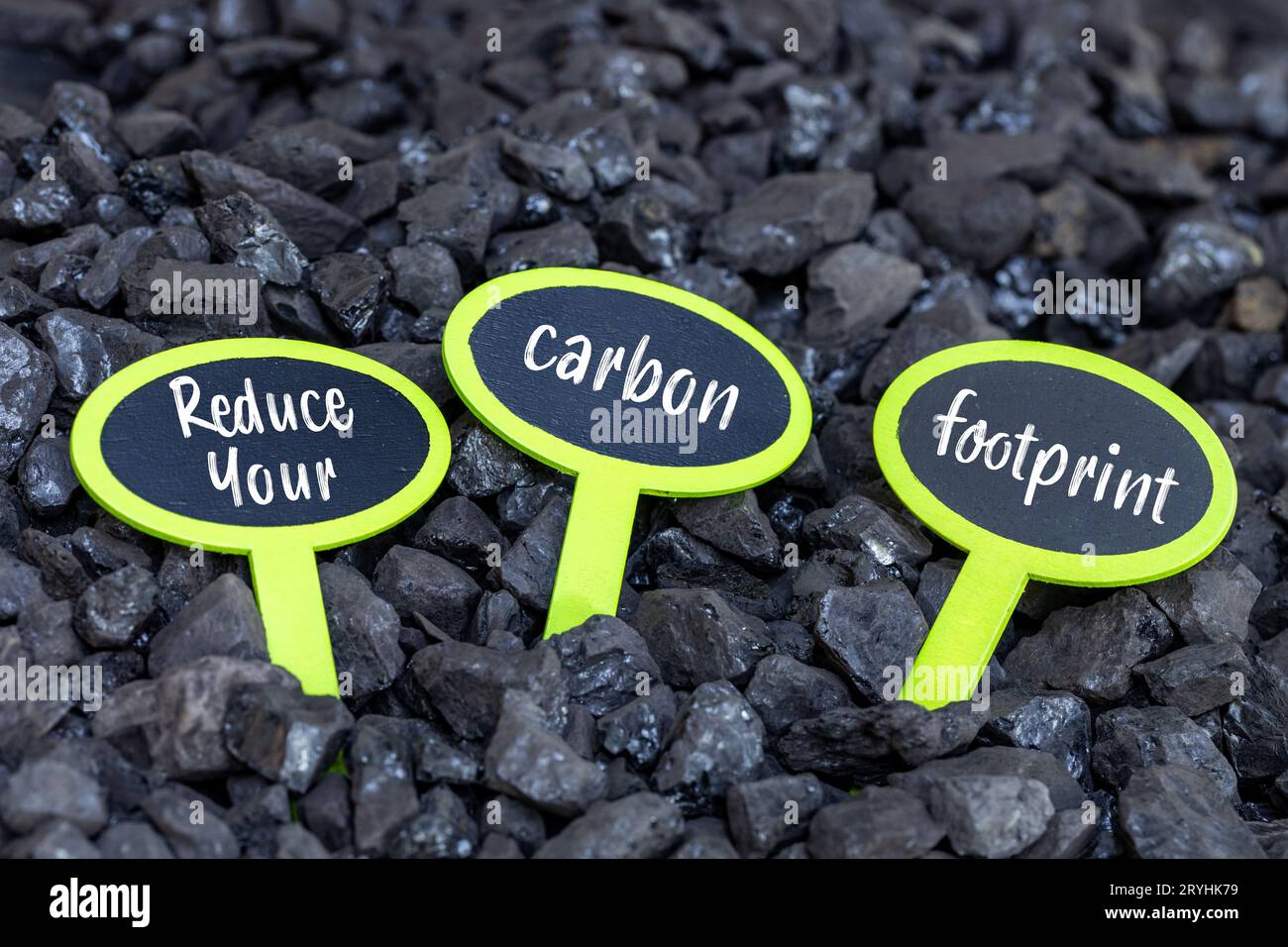 Coal heap and green signs saying reduce your carbon footprint ...