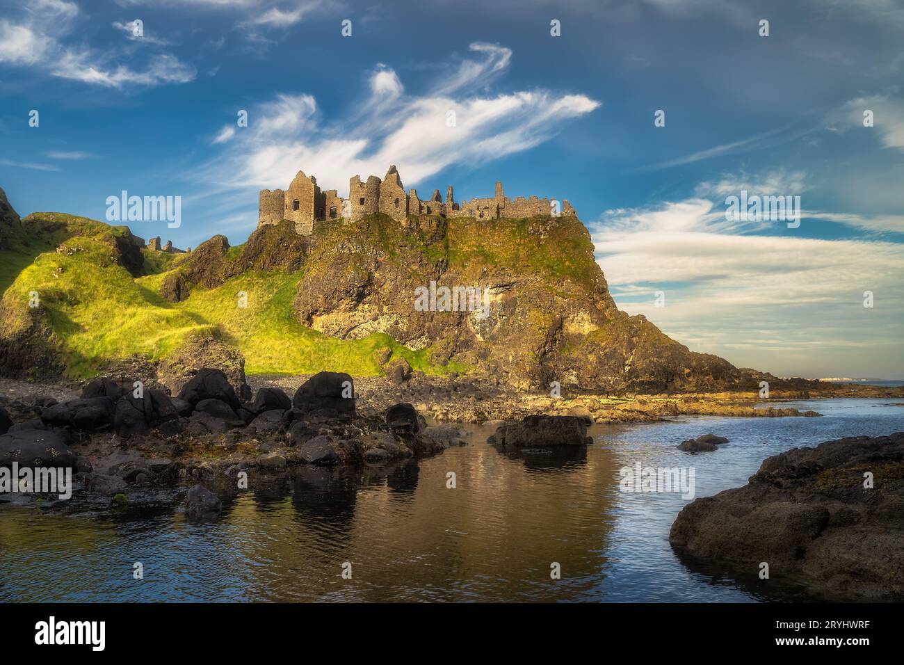 View from a shoreline on Dunluce Castle nested on the edge of cliff ...