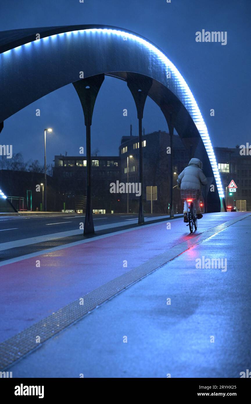 Woman with gray jacket riding a bicycle in rain over illuminated ...
