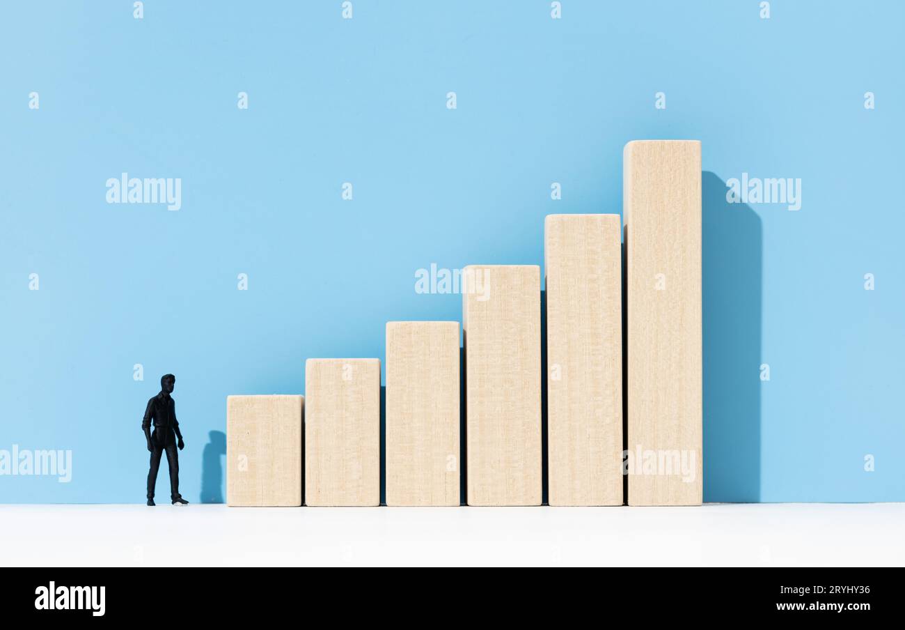 Human figurine looking at a growing bar chart. Career development ...