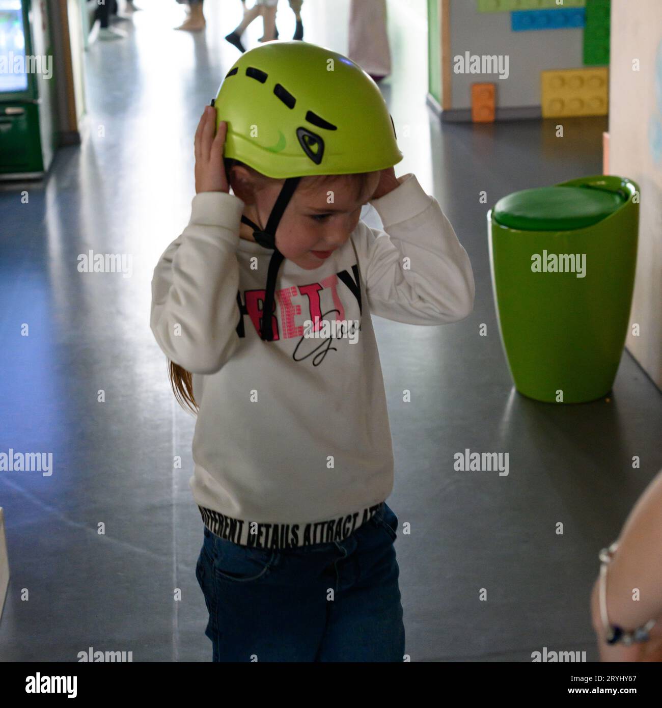 A helmet is put on the Little Girl's head as protection on a cable car ...