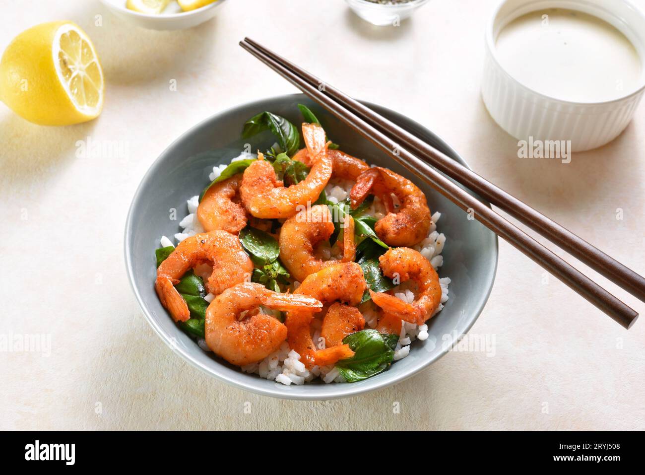 Roasted prawn with basil leaves and rice in bowl on light stone ...