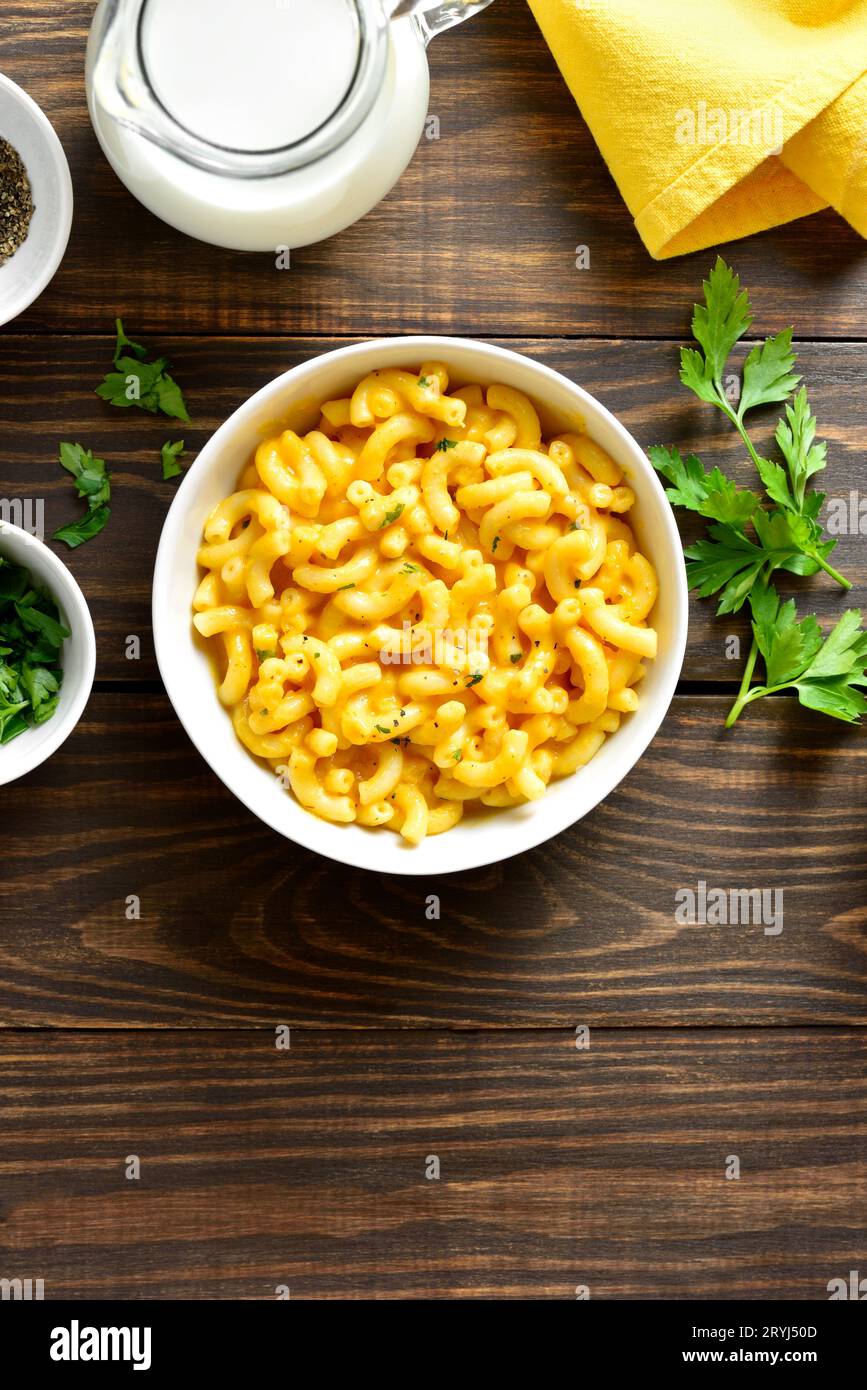 Homemade macaroni and cheese in white bowl over wooden background with ...