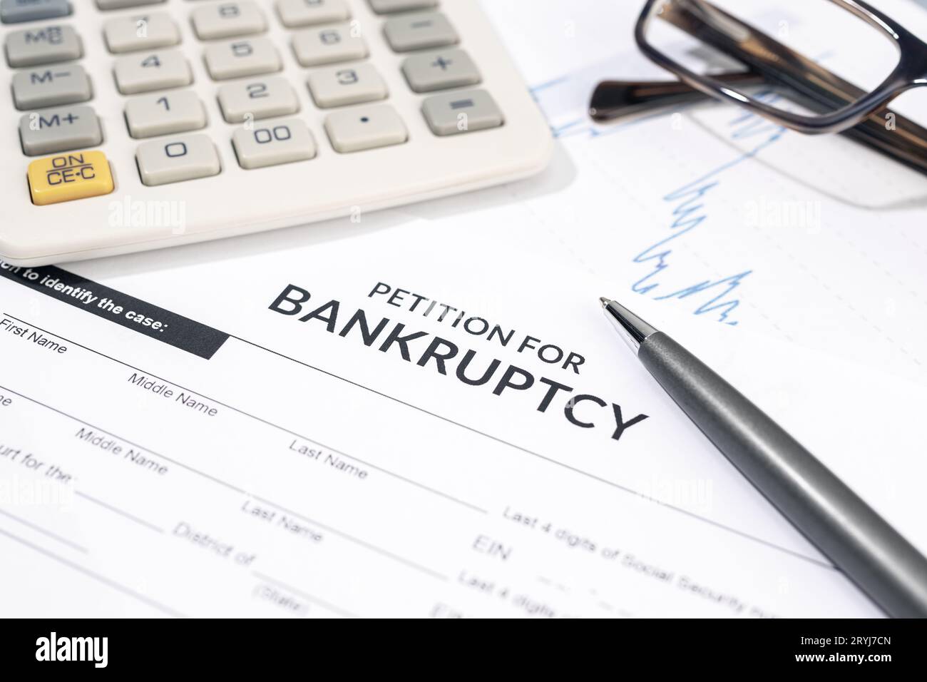 Bankruptcy form, calculator and pen on desk. Personal injury claim form ...