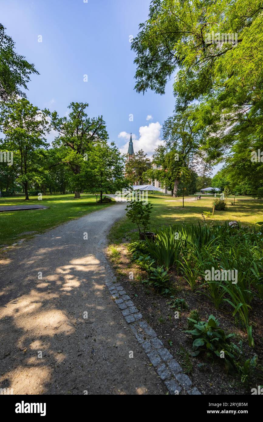 Long curvy path in beautiful green park with tower of building at sunny ...