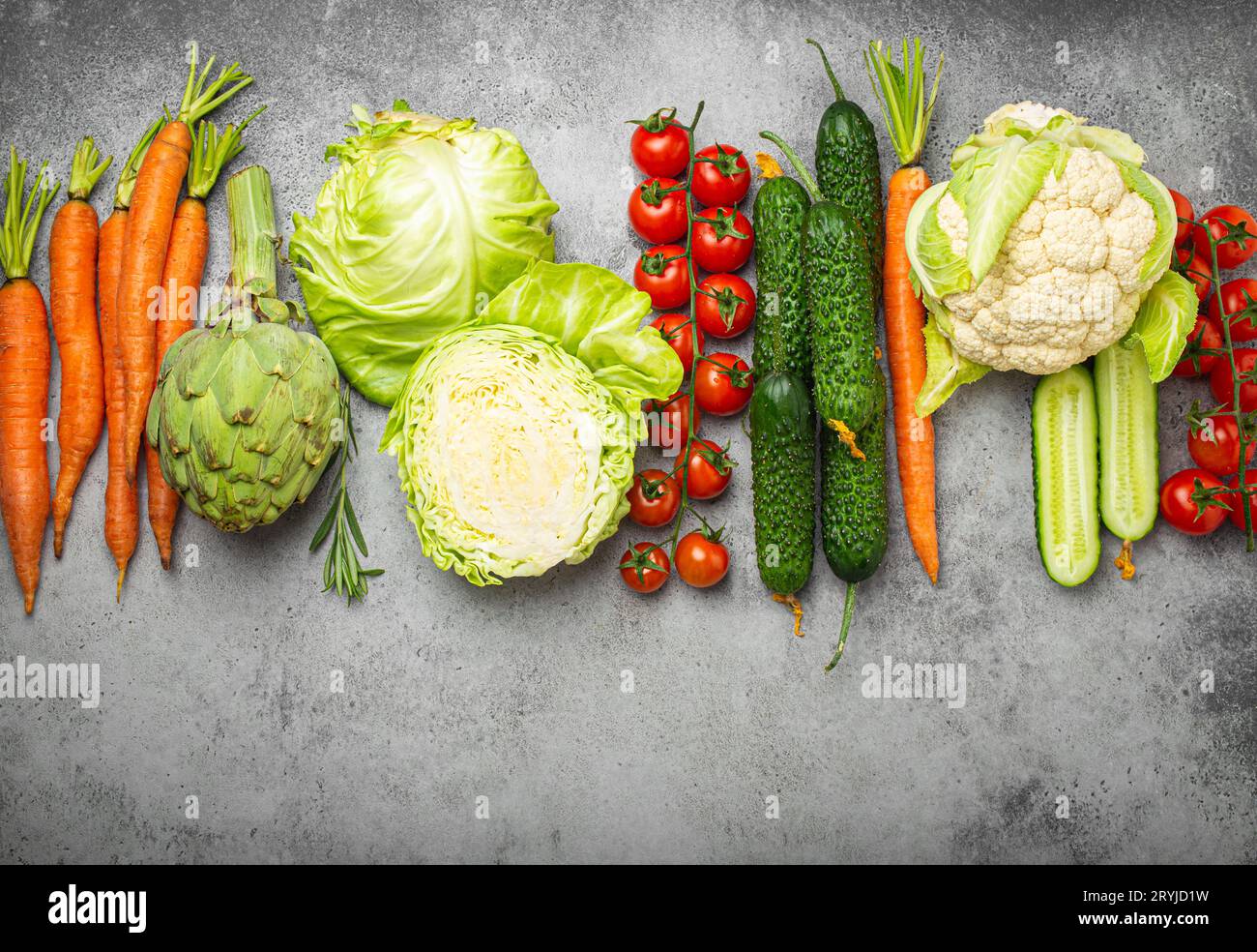 Fresh assorted organic vegetables arranged in line on rustic grey stone ...