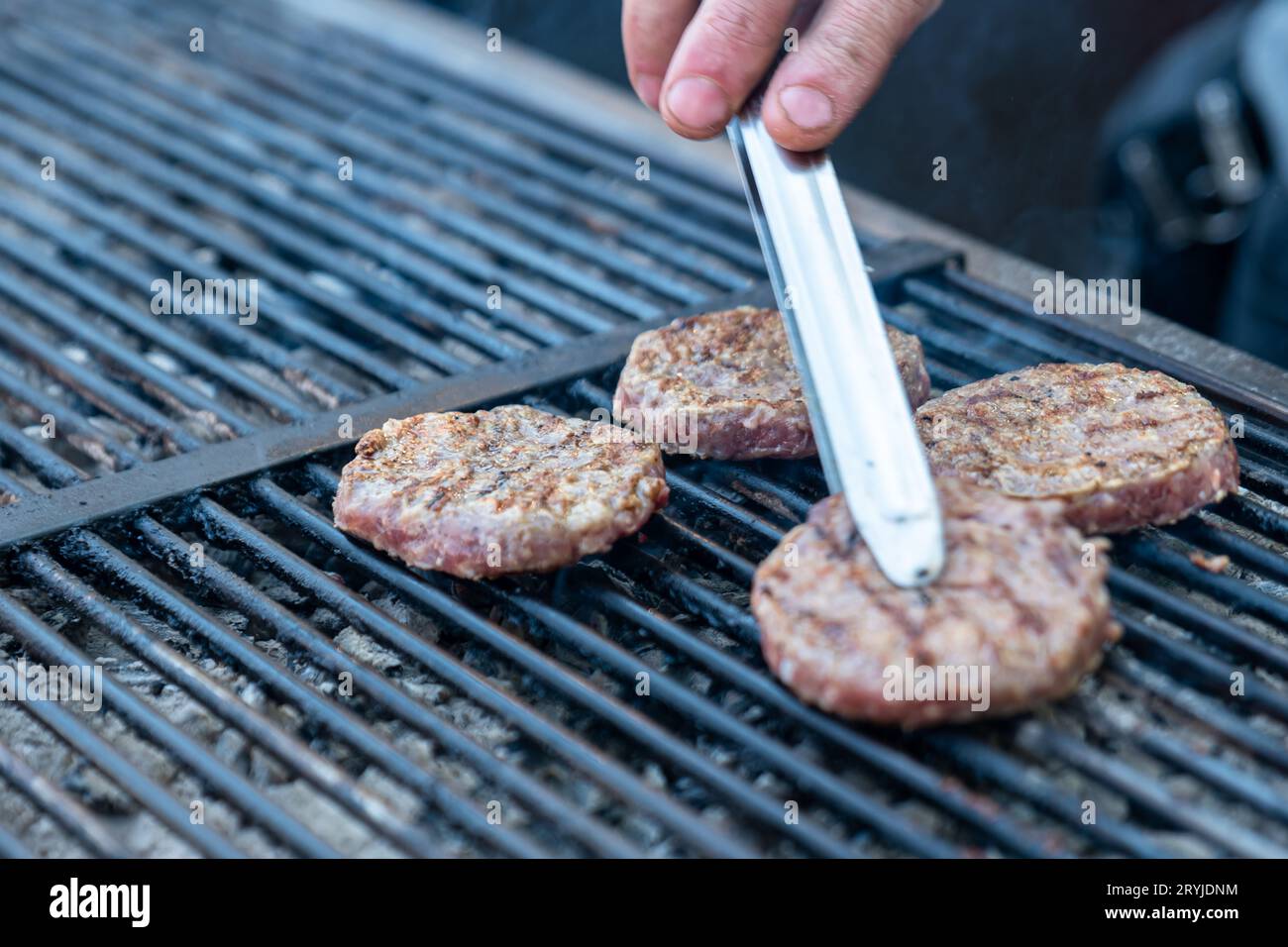 Chef making burger meat at the open air restaurant grill. Festival food ...
