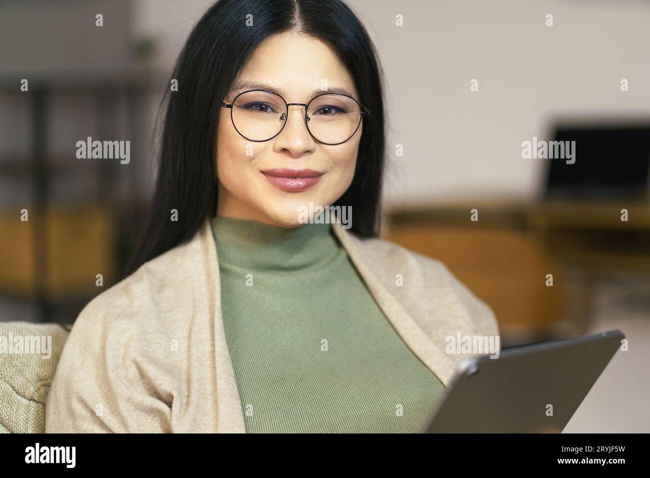 Cheerful middle-aged Asian woman wearing glasses enjoys browsing ...