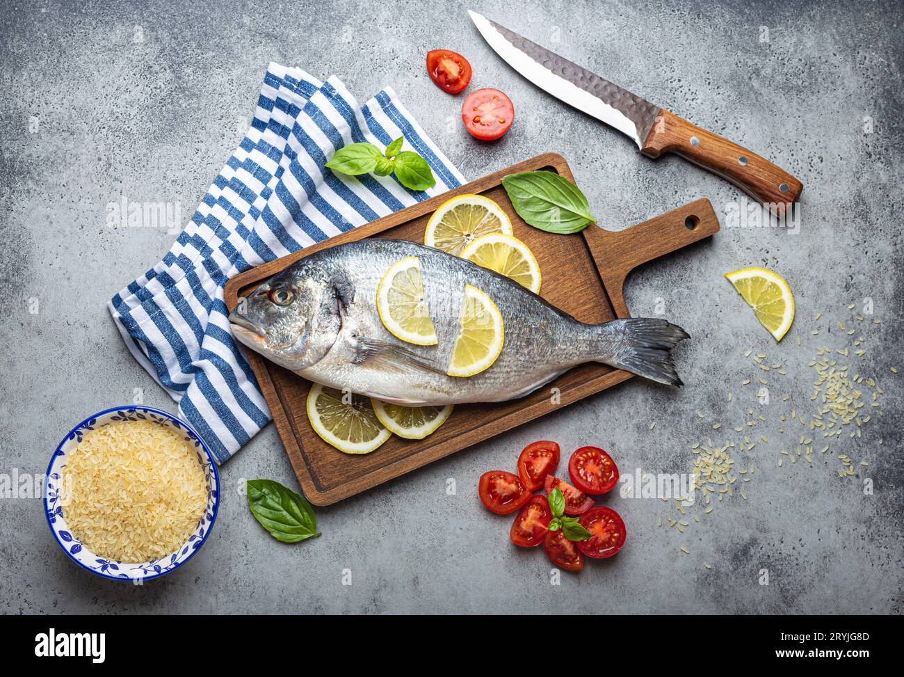 Raw fish dorado with ingredients lemon, fresh basil, cut cherry ...
