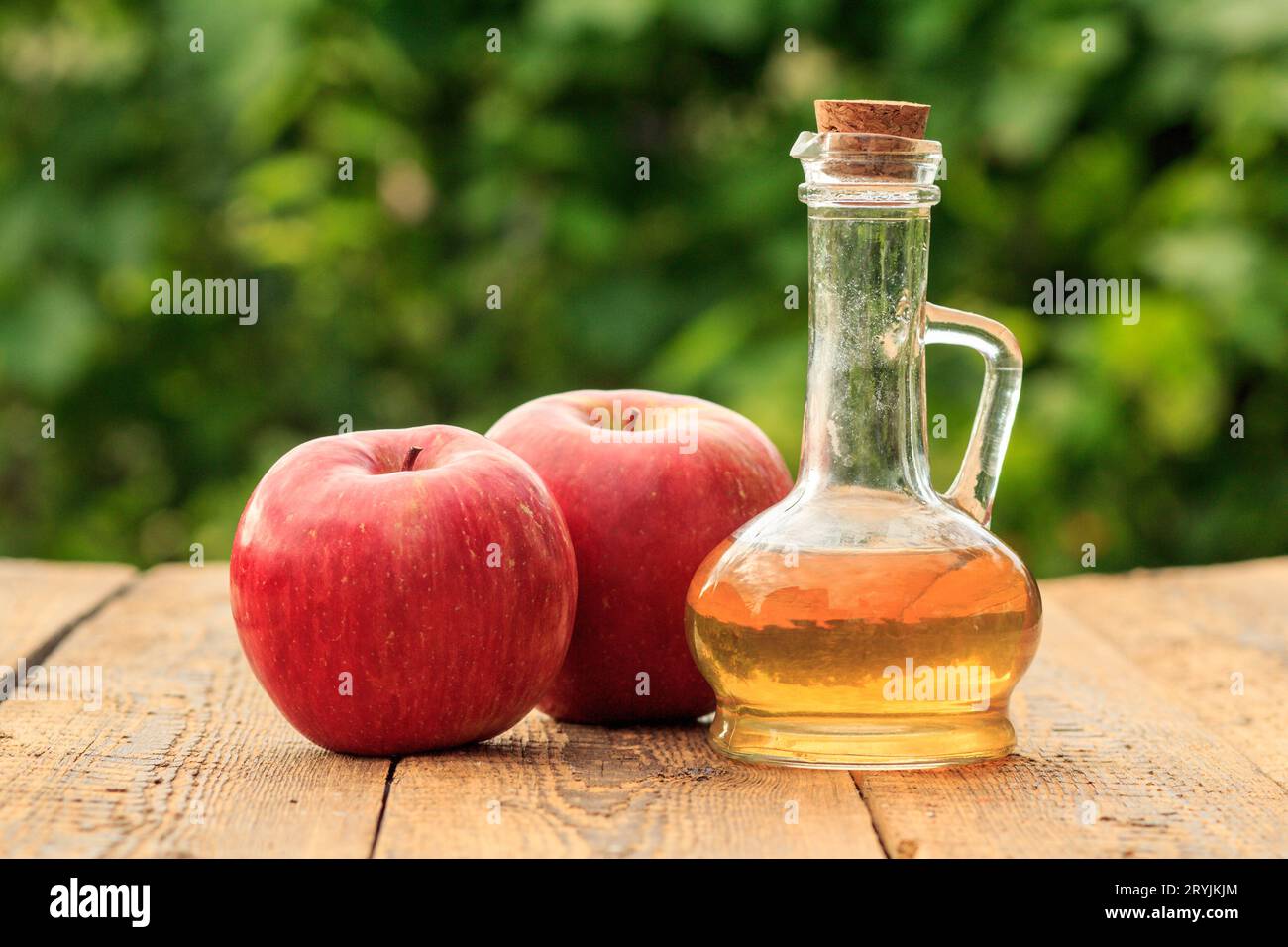 Apple vinegar in glass bottle and red apples on wooden boards with ...