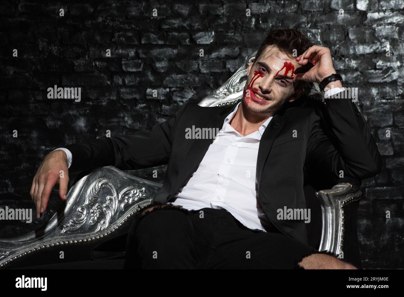 Smiling handsome vampire chilling on silver couch Stock Photo - Alamy