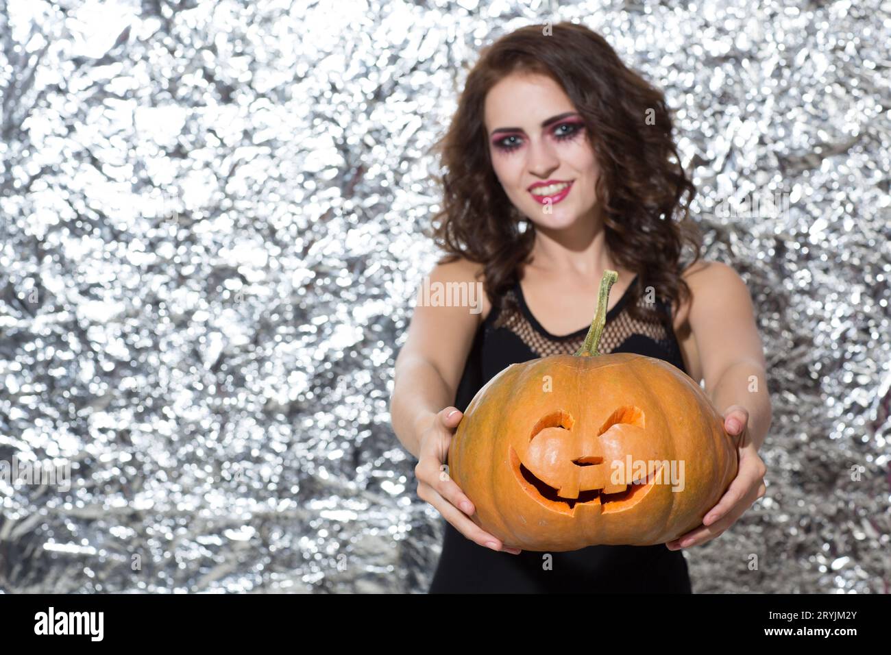 Pretty woman with bright make up, giving pumpkin to camera Stock Photo ...