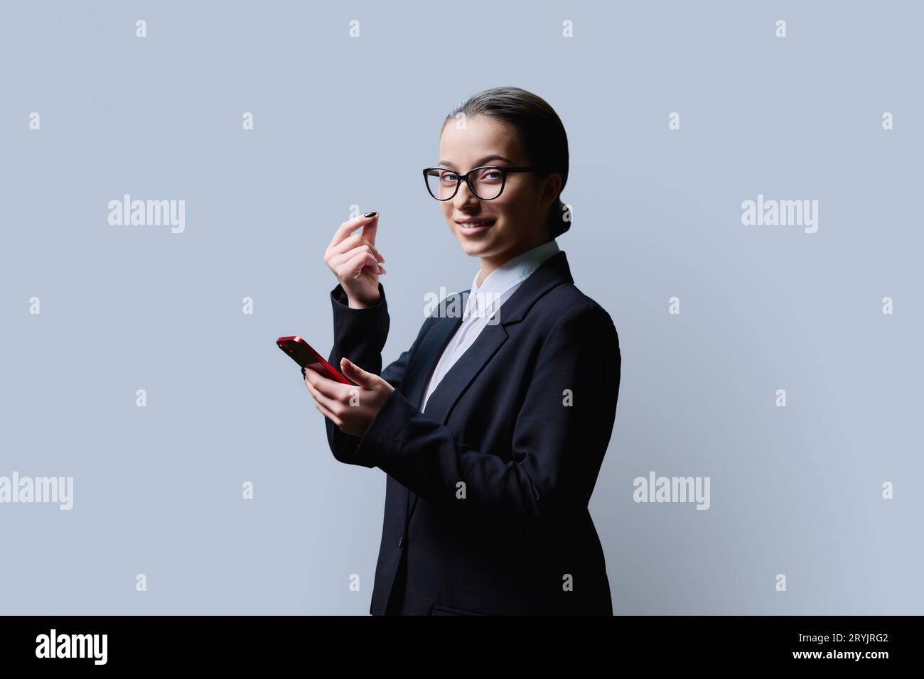 Teenage girl making money gesture, rubbing her fingers, on grey ...