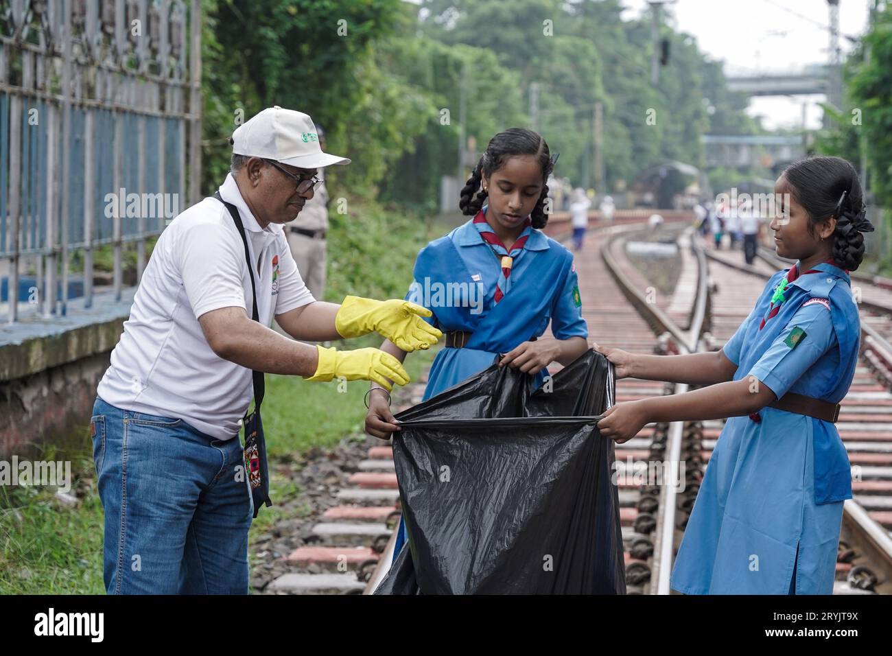 A man and students collect garbage from the rail line as they take part ...