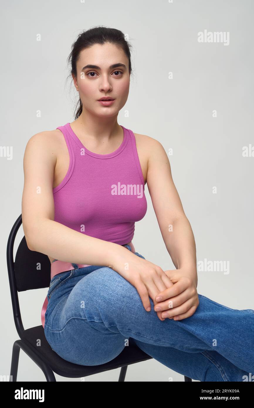 Confident young woman sitting on chair Stock Photo - Alamy