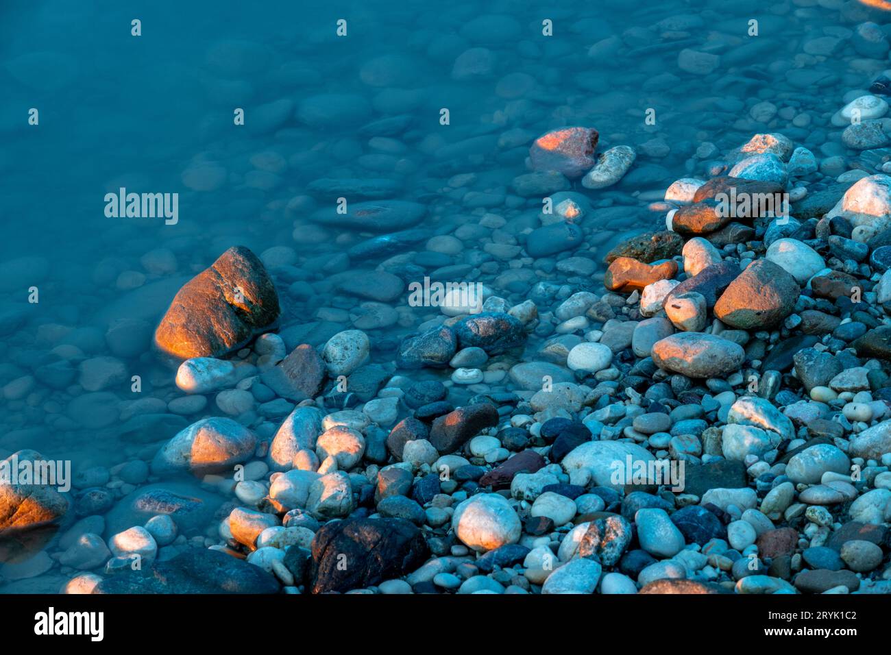 Colorful pebbles on the blue river shore, photographed at the last ...