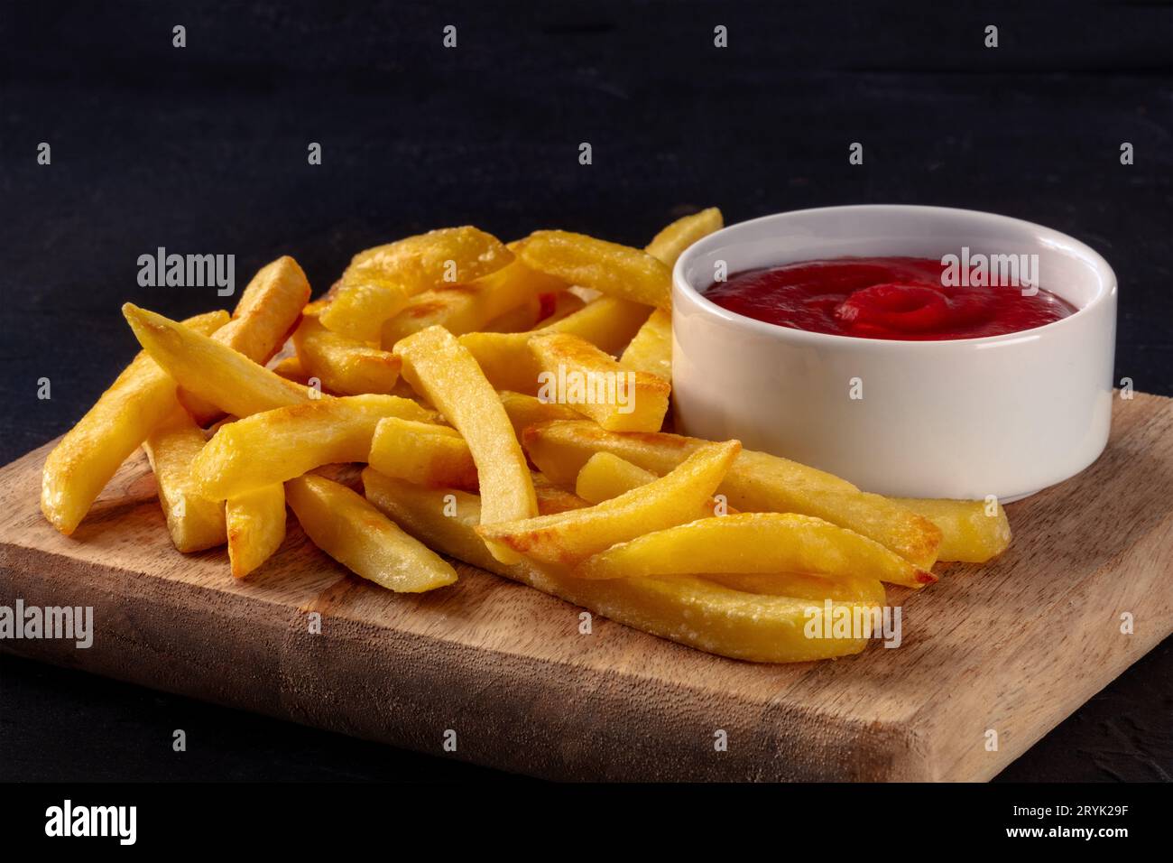 French fries, potato snack with ketchup, fast food on a black slate ...