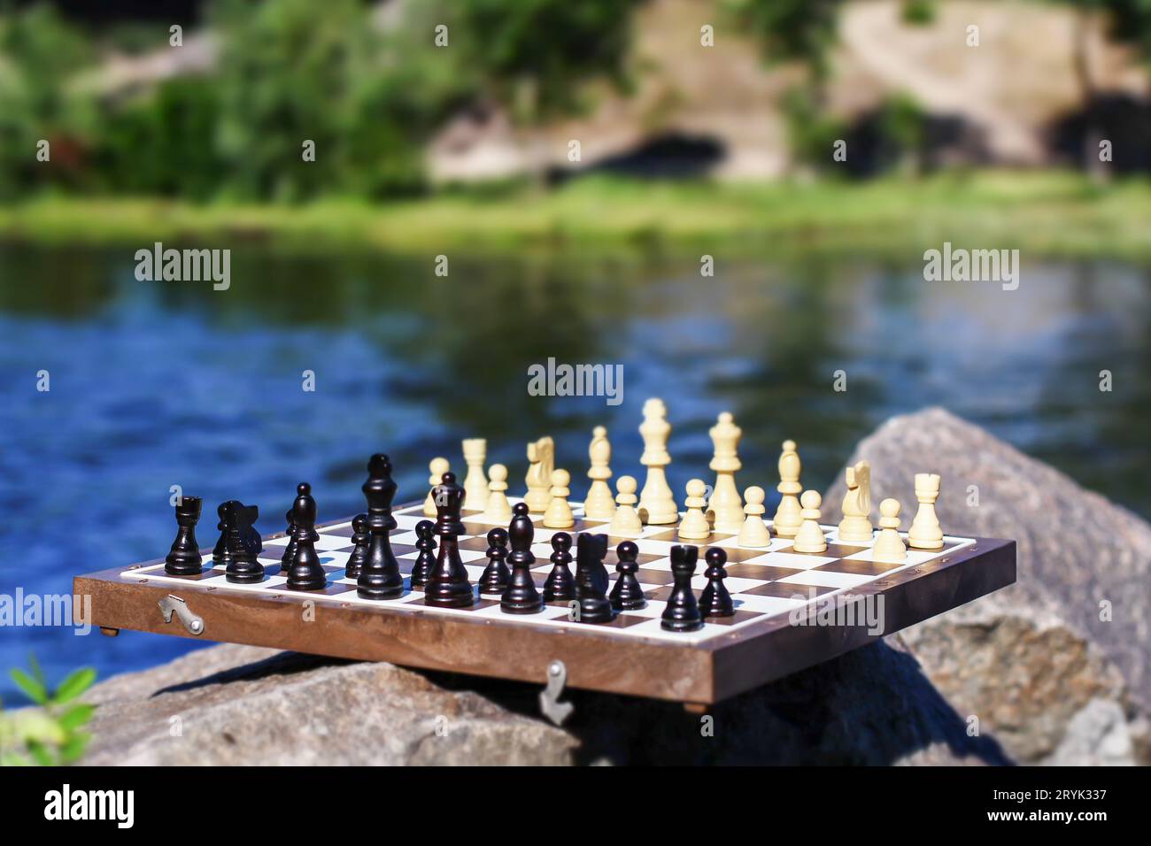 Chess board with chess pieces on a rock with the river embankment ...