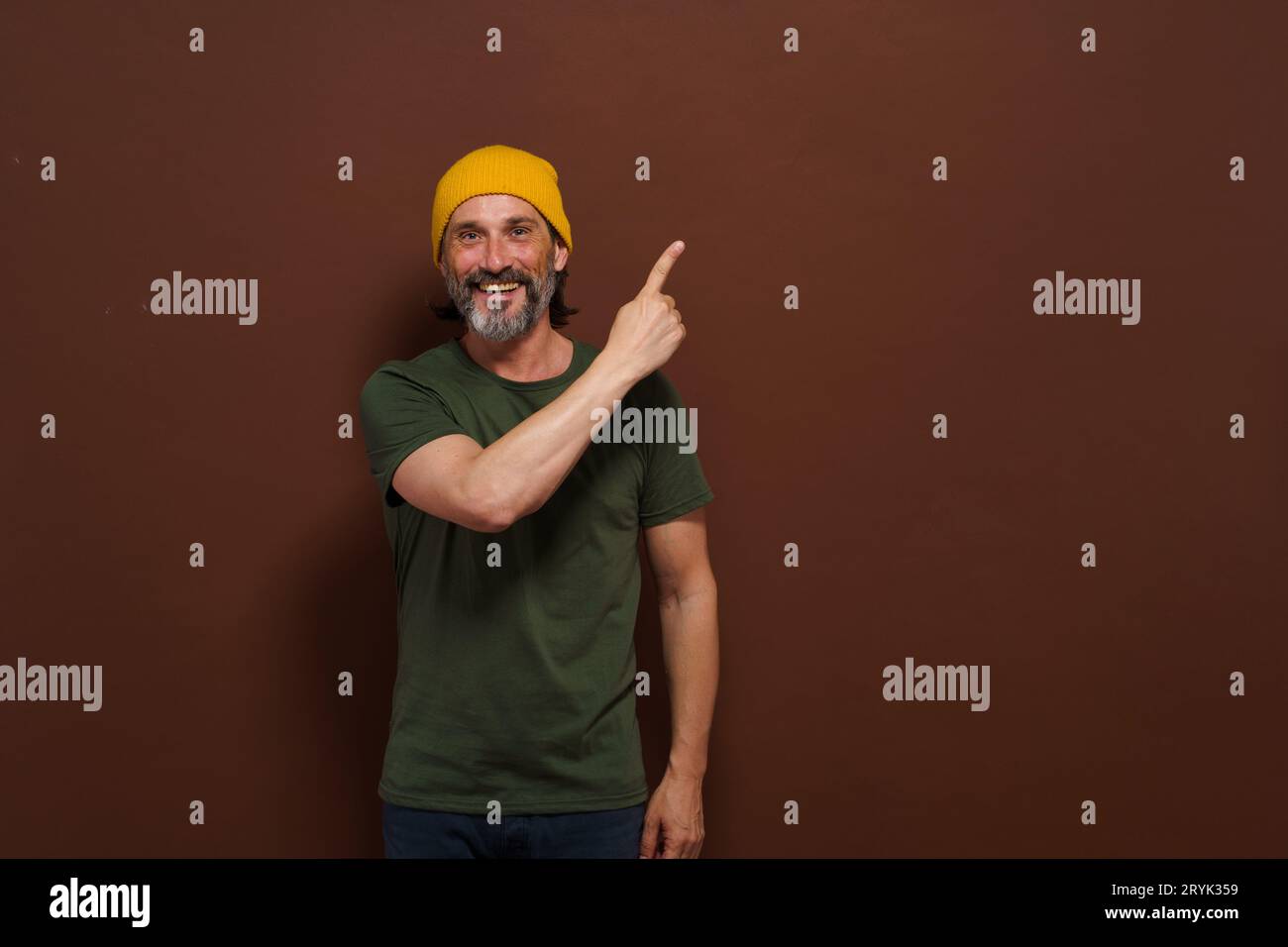Excited smiling Caucasian man in a yellow hat points his hand to the ...
