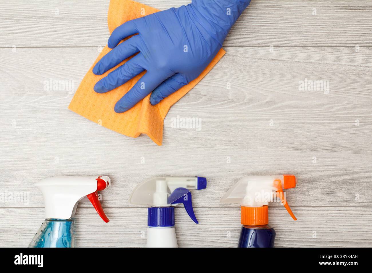 Hand in a rubber glove holding the dust napkin with the bottles of ...