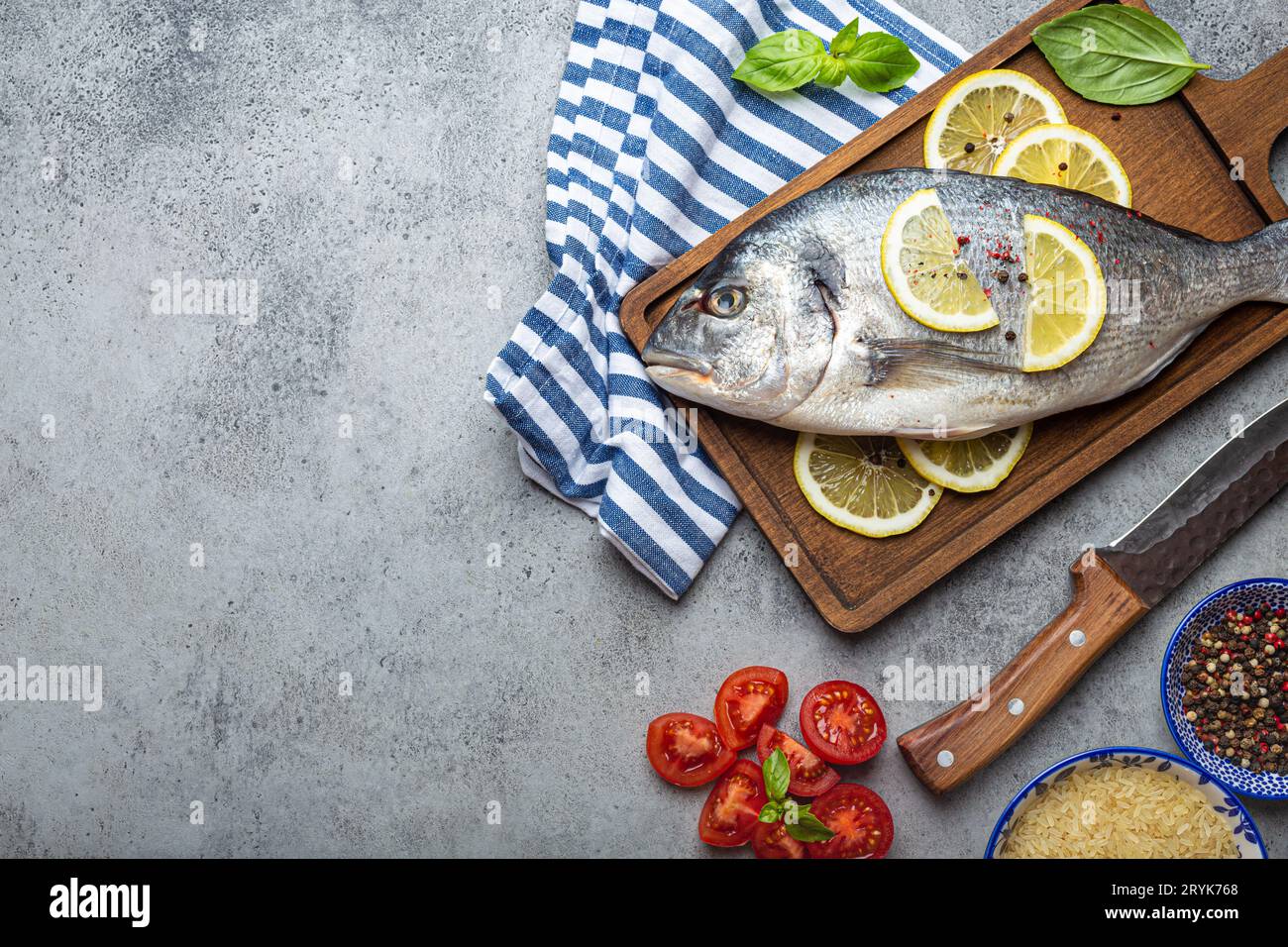 Raw fish dorado with ingredients lemon, fresh basil, cut cherry ...