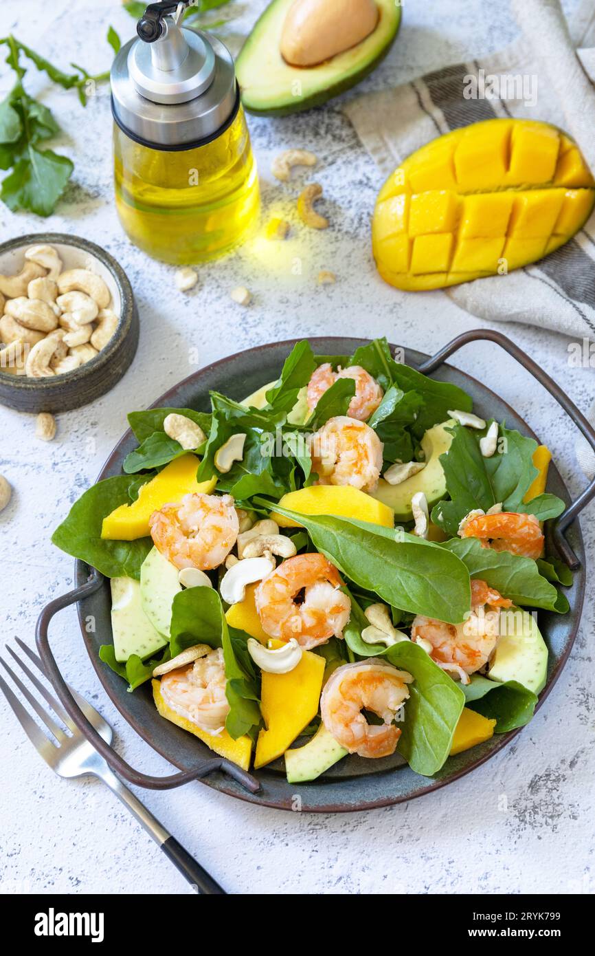 Healthy diet salad with arugula, spinach, mango, avocado, shrimp, pecans and vinaigrette ...