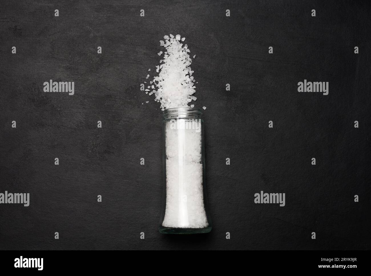 Large crystals of salt in a glass transparent bottle are scattered on a ...