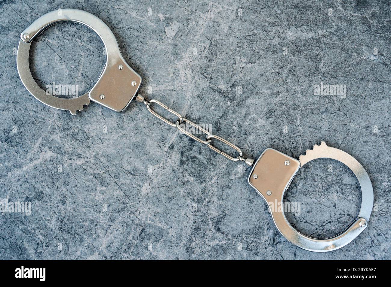 Closed metal handcuffs on the cement background Stock Photo - Alamy